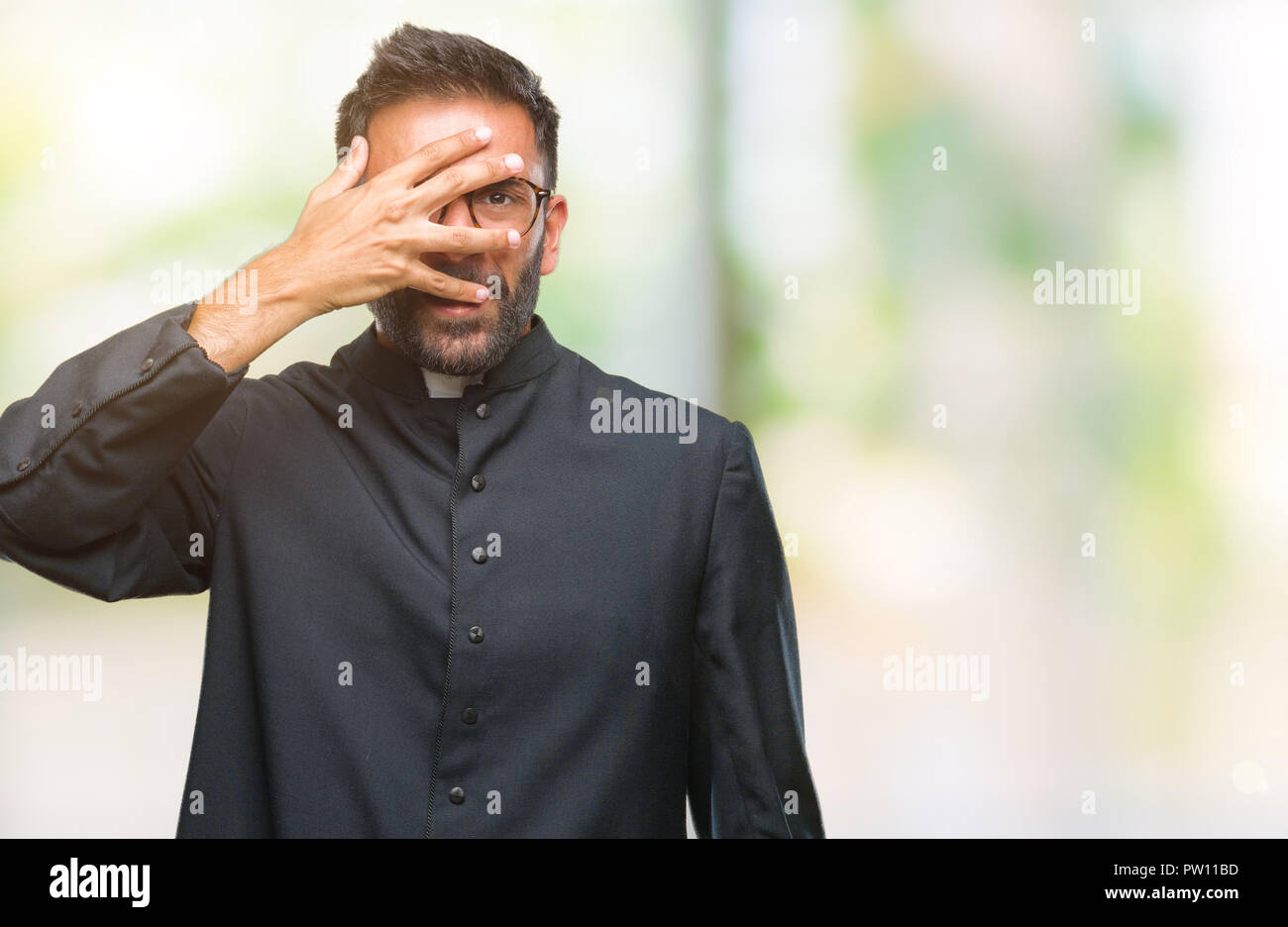 Adult hispanic catholic priest man over isolated background peeking in ...