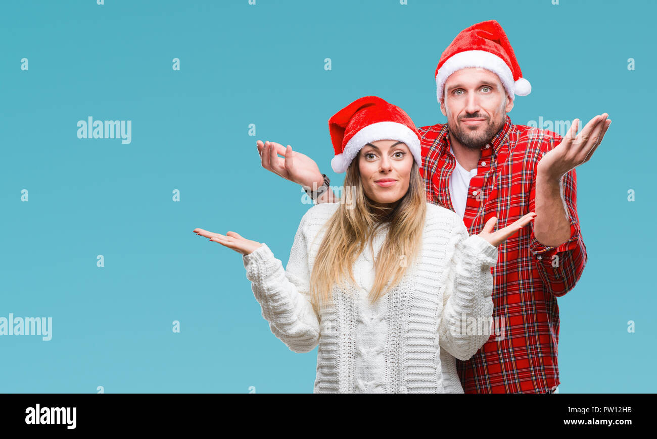Young couple in love wearing christmas hat over isolated background ...