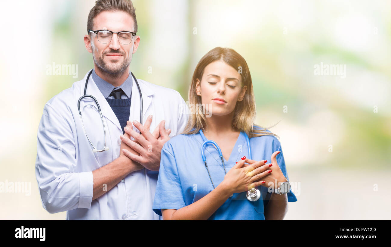 Young couple of doctor and surgeon over isolated background smiling ...