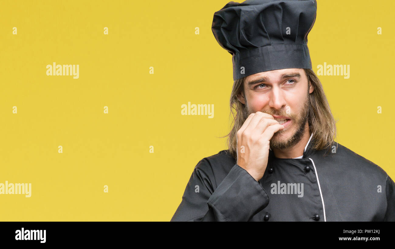 Young handsome cook man with long hair over isolated background looking ...