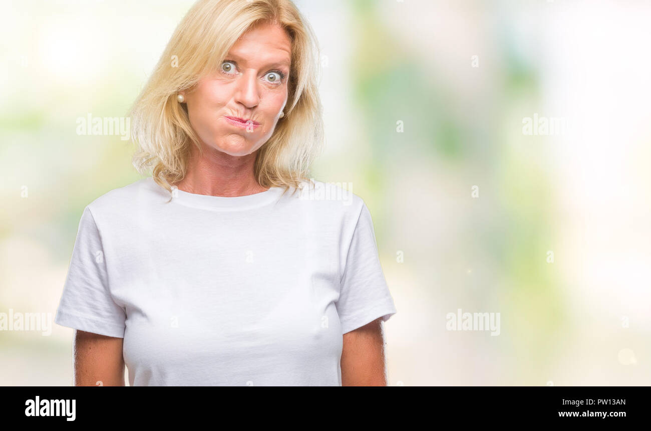 Middle age blonde woman over isolated background puffing cheeks with ...