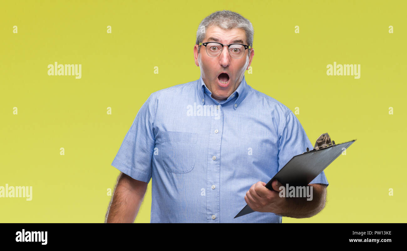 Handsome senior inspector man holding clipboard over isolated ...