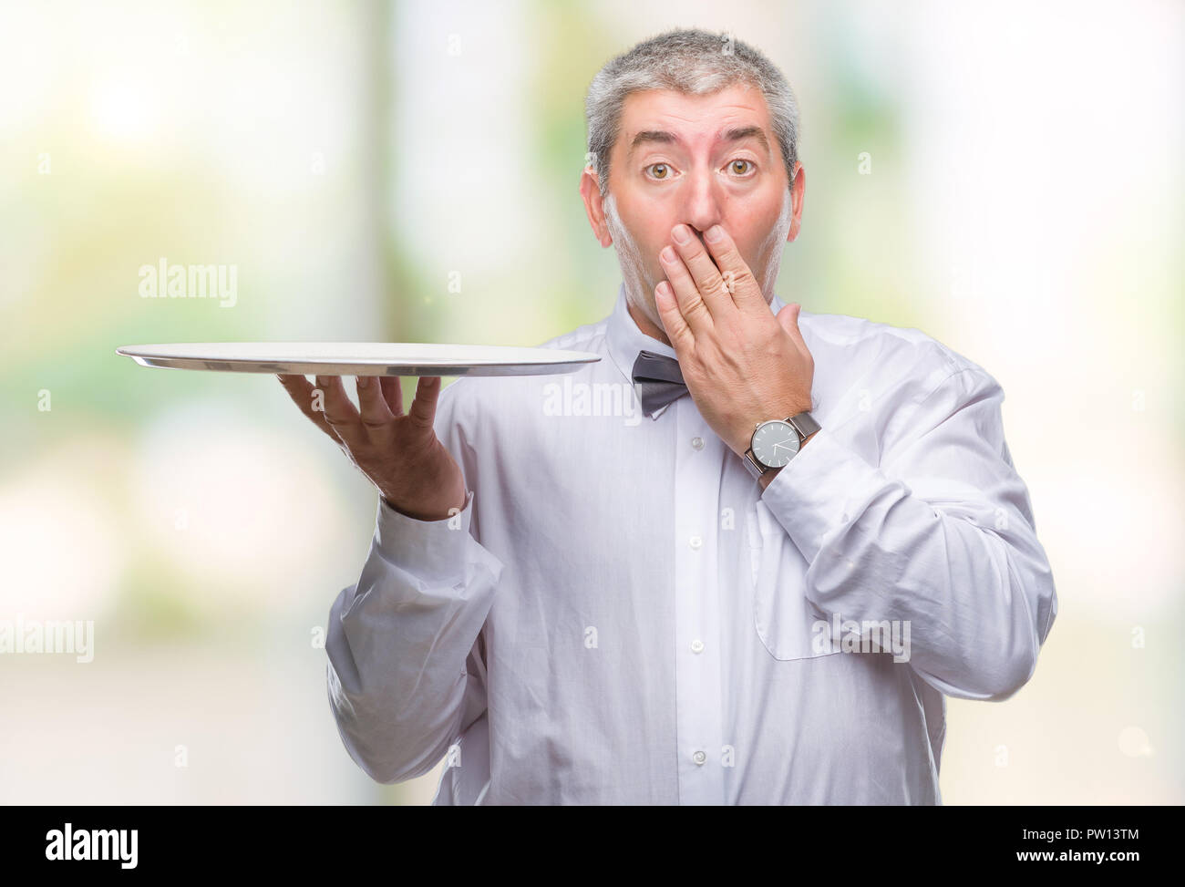 Handsome senior waiter man holding silver tray over isolated background ...