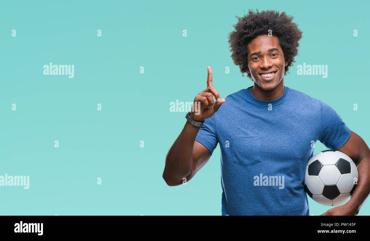 Afro american man holding football ball over isolated background ...