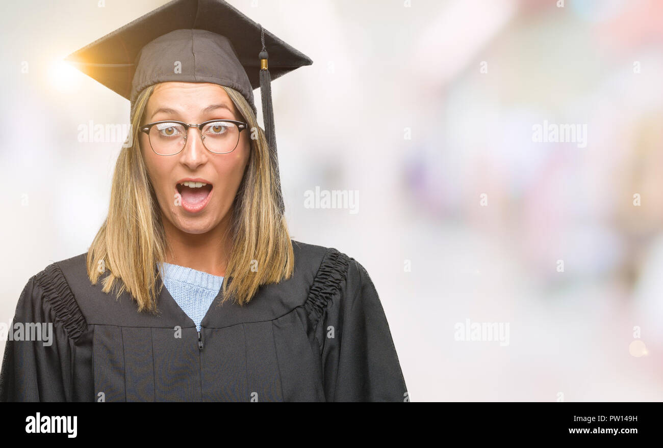 Young beautiful woman wearing graduated uniform over isolated ...