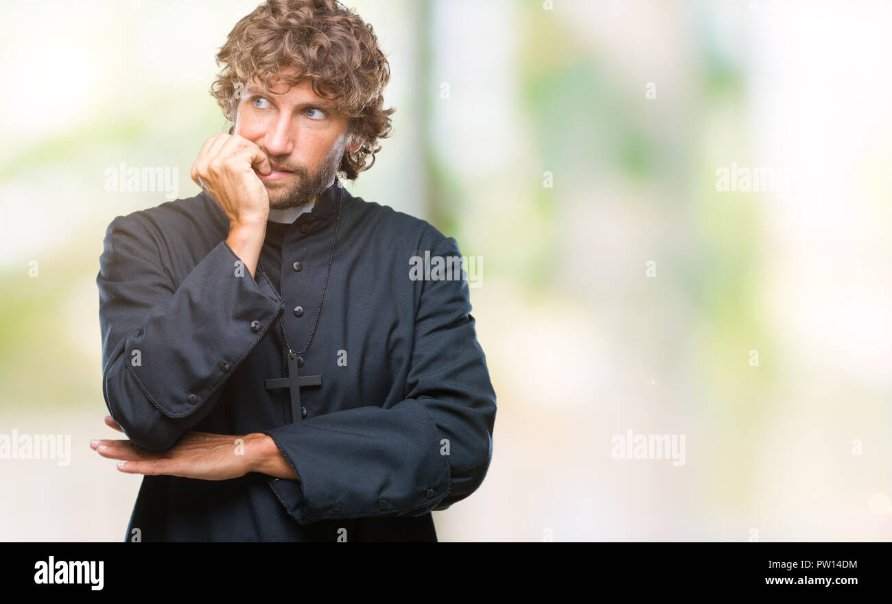 Handsome hispanic catholic priest man over isolated background looking ...