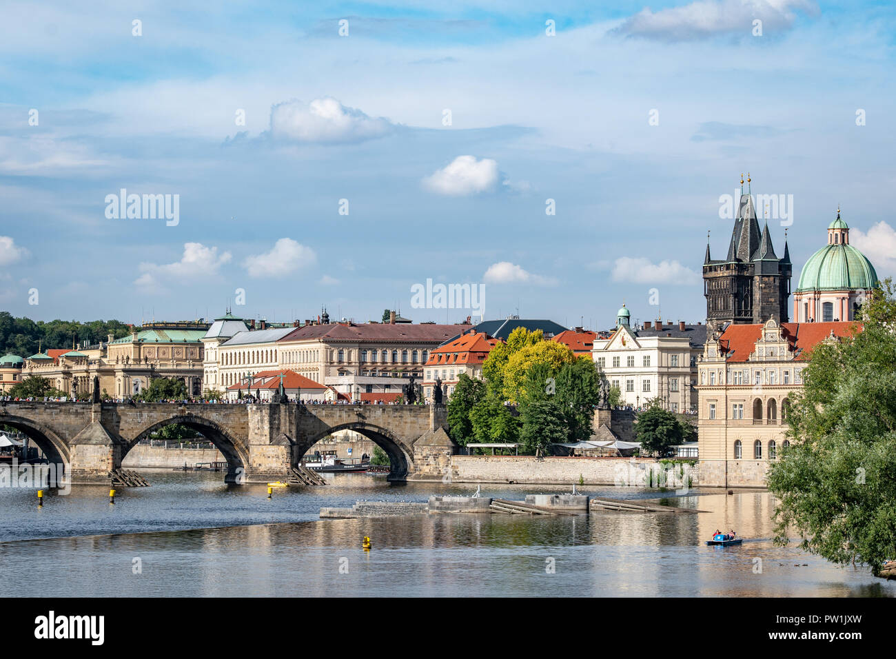 Side perspective of pedestrians crossing Charles Bridge with scenic view bridge tower in Prague ...