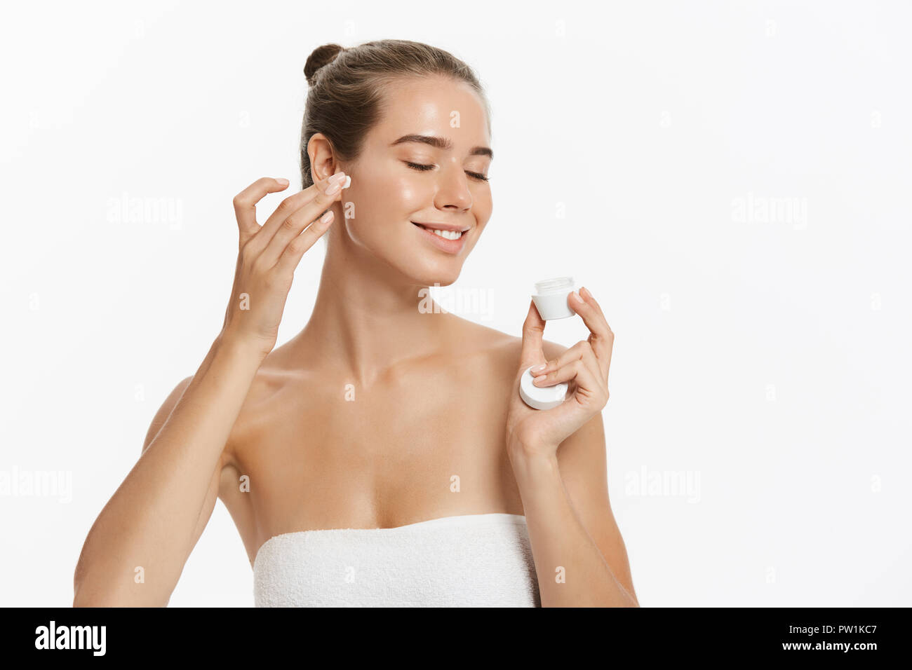 Beautiful Young Woman Applying Cosmetic Cream Treatment On Her Face