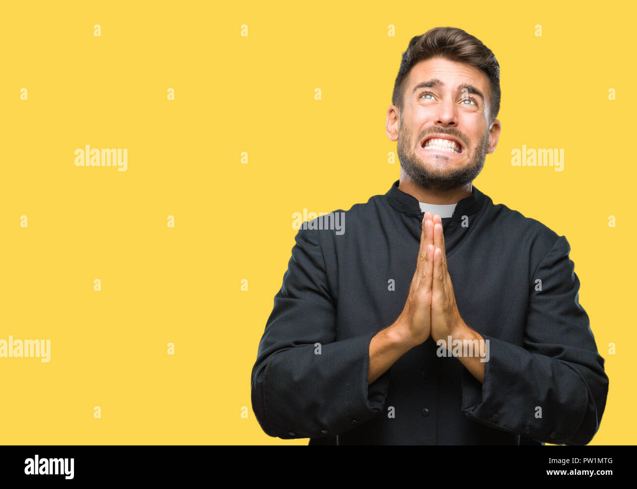 Young catholic christian priest man over isolated background begging ...