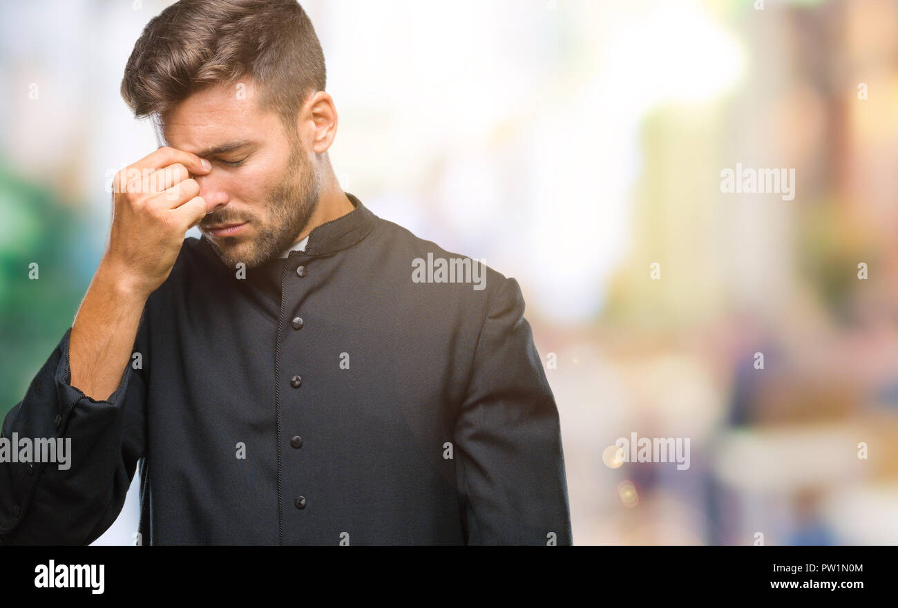Young catholic christian priest man over isolated background tired ...