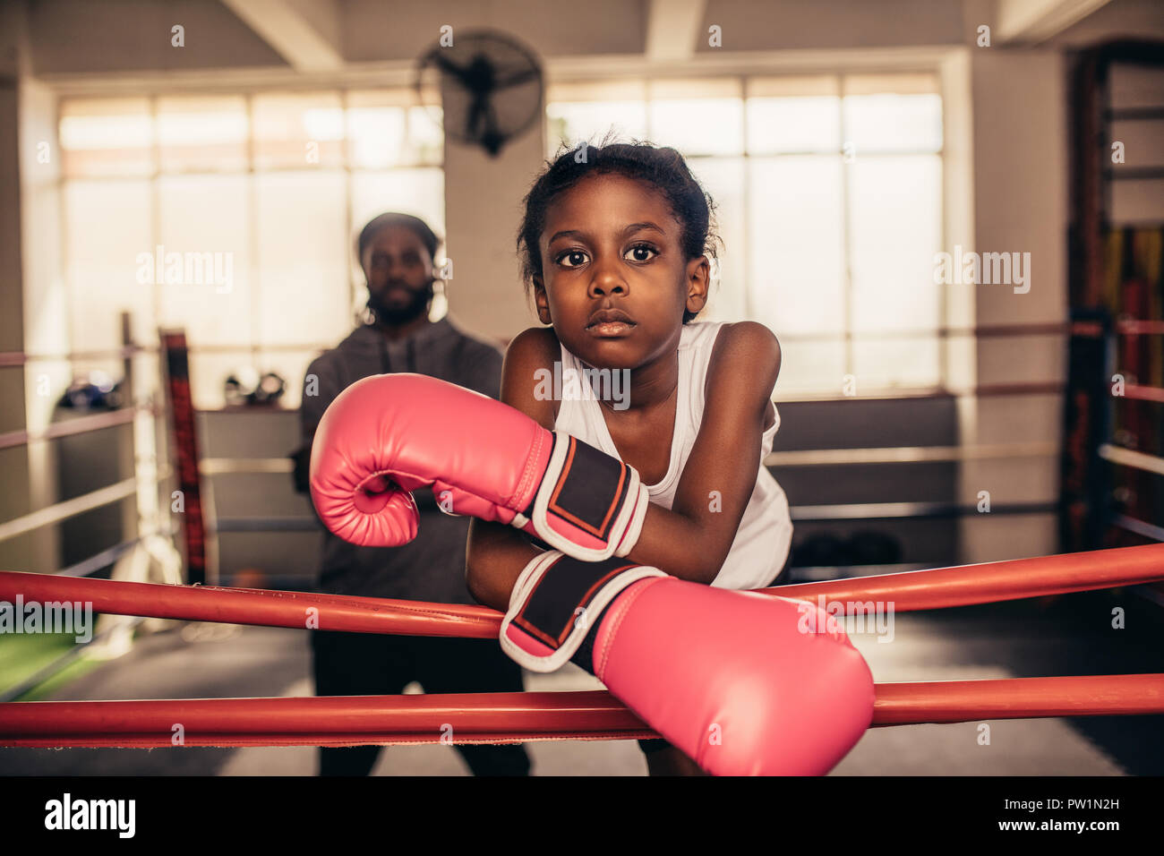Confident looking boxing kid standing inside a boxing ring with her ...