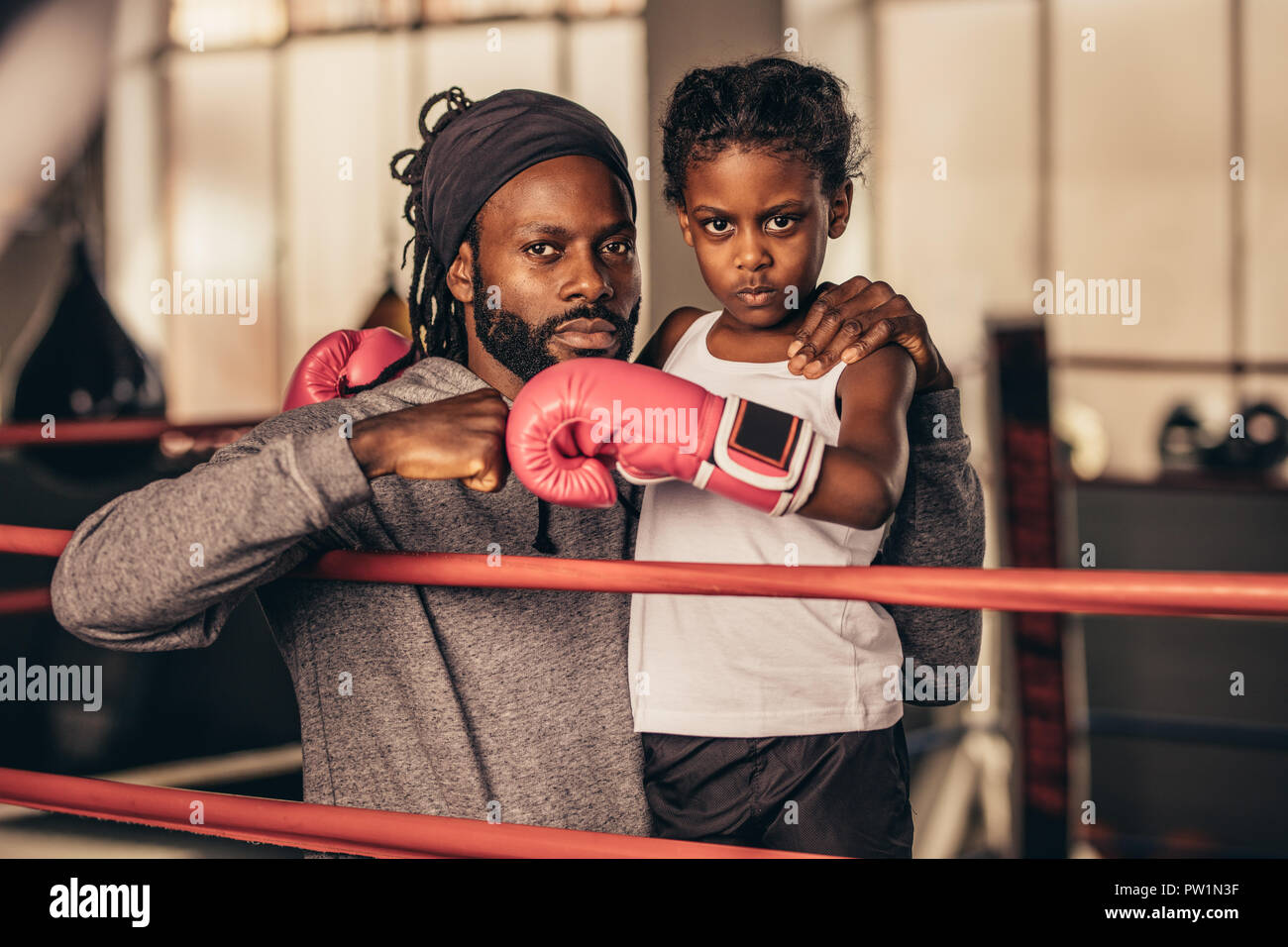 Boxing kid wearing boxing gloves standing with her coach knocking their ...