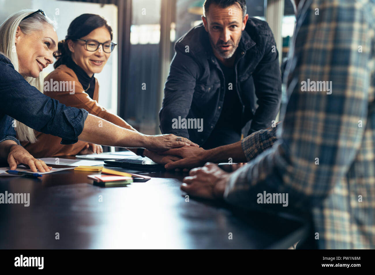 Group of business people putting their hands together over a table with ...
