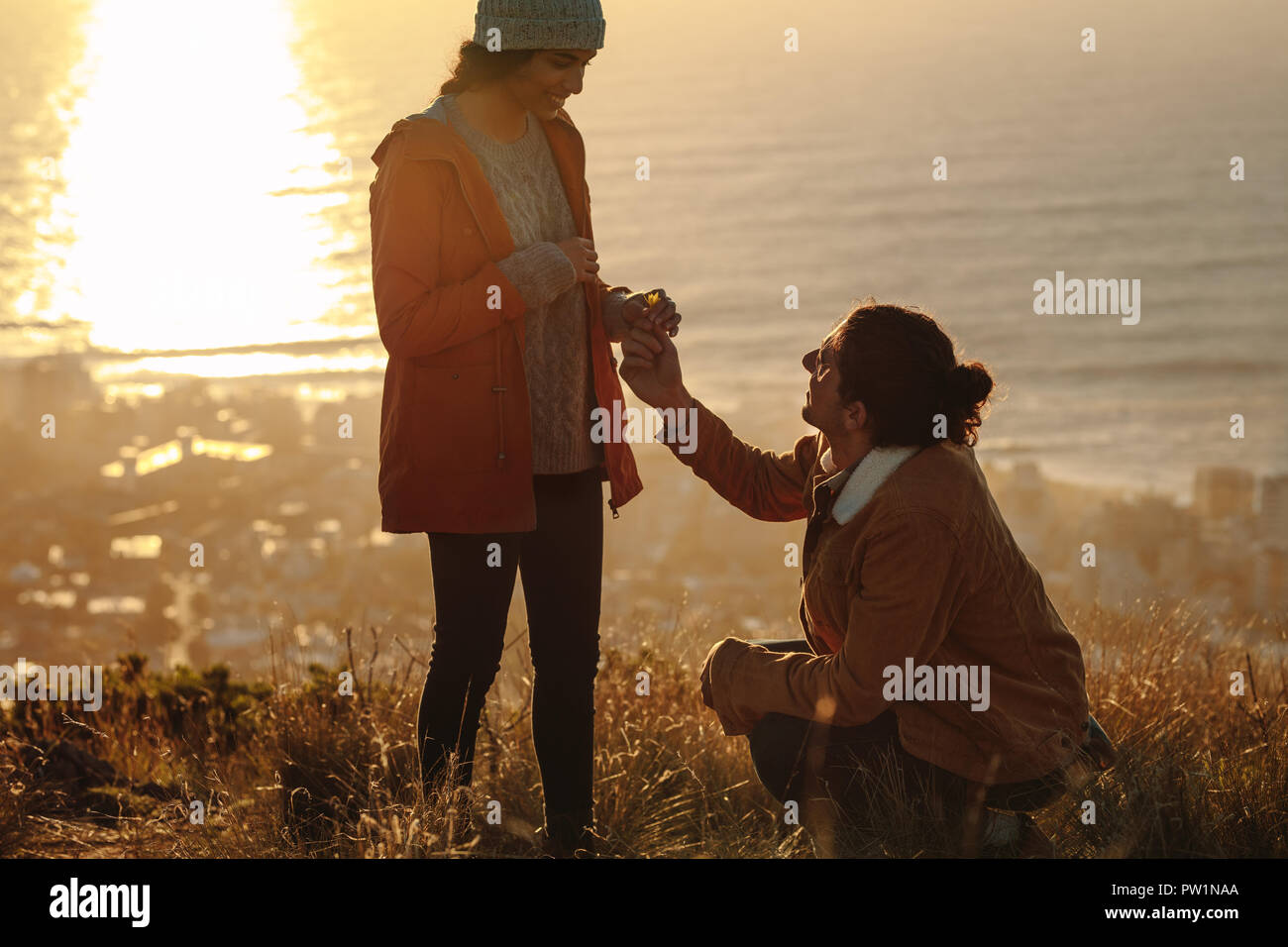 Man making marriage proposal to his girlfriend on the mountain peak at ...