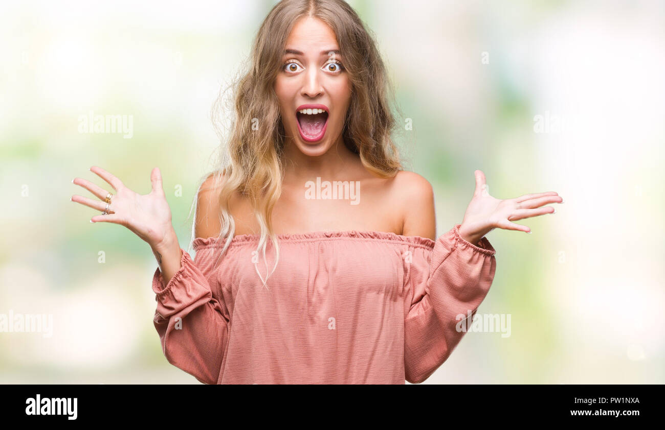 Beautiful young blonde woman over isolated background celebrating crazy ...