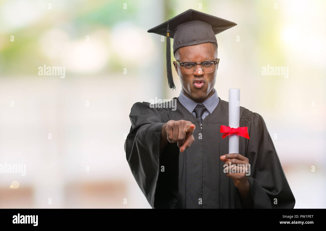 Young graduated african american man holding degree over isolated ...