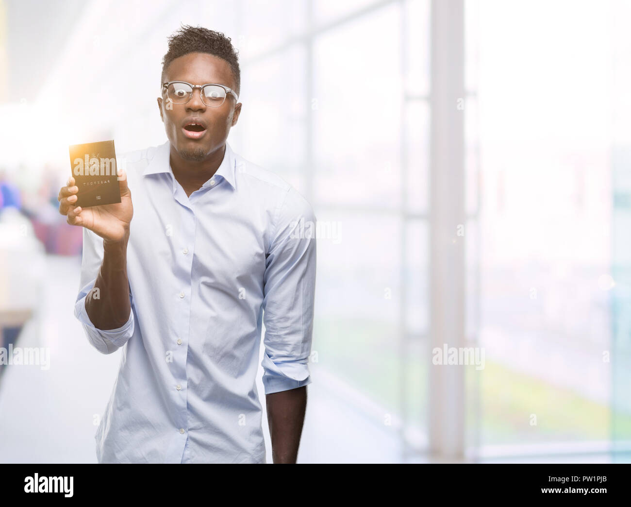 Young african american man holding australian passport scared in shock ...