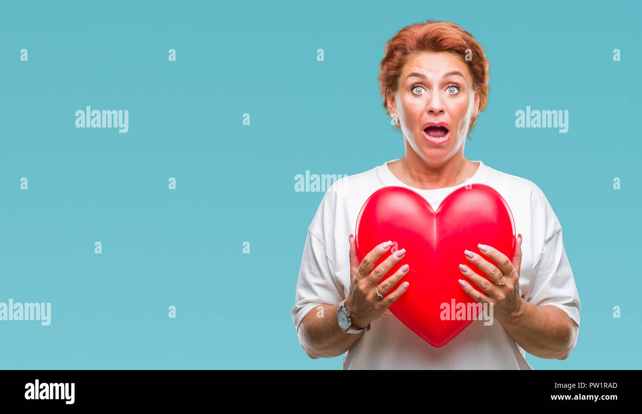 Senior caucasian woman holding red heart in love over isolated ...