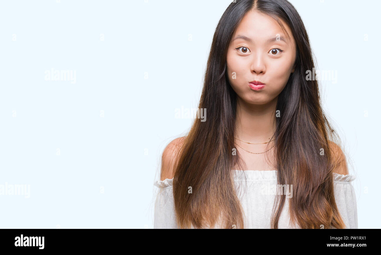 Young asian woman over isolated background puffing cheeks with funny ...