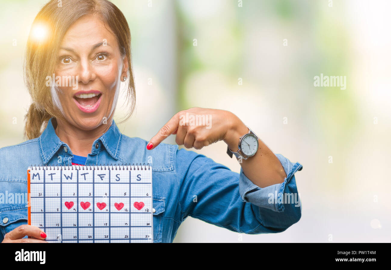Middle age senior hispanic woman holding menstruation calendar over ...