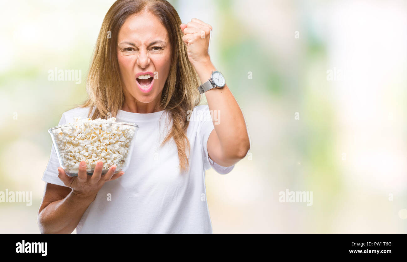 Middle age hispanic woman eating popcorn over isolated background ...