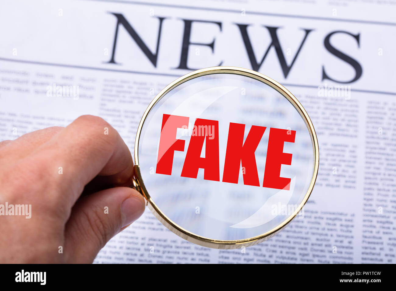 Man's Hand Examining Fake News On Newspaper Through Magnifying Glass ...