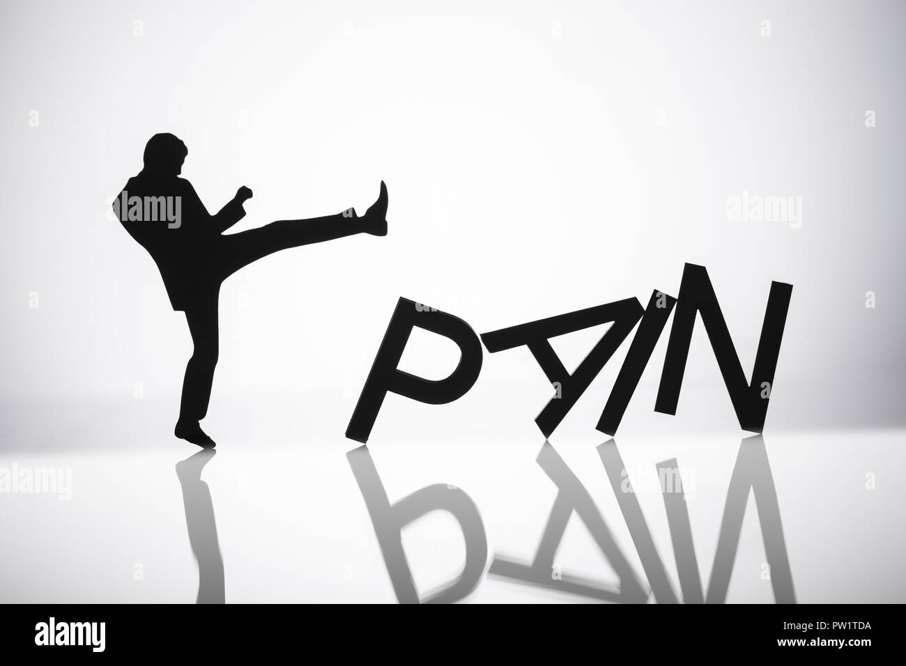 Silhouette Of A Person Kicking Pain Word On Reflective Background Stock ...