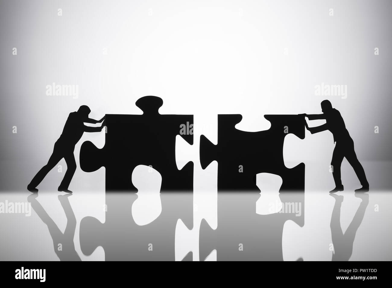 Silhouette Of Two Businesspeople Joining Jigsaw Puzzle Pieces On ...