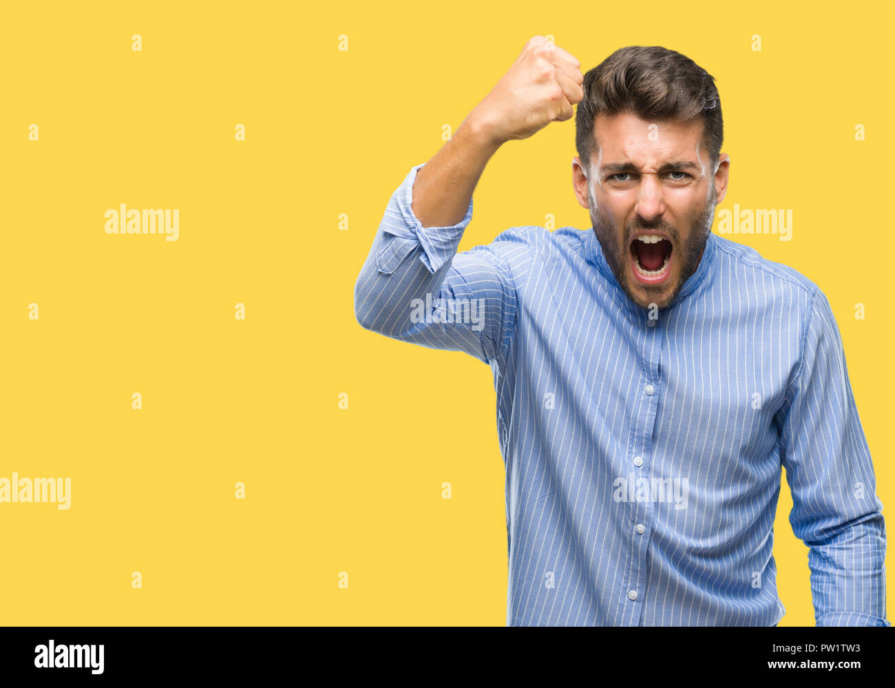 Young handsome man over isolated background angry and mad raising fist ...