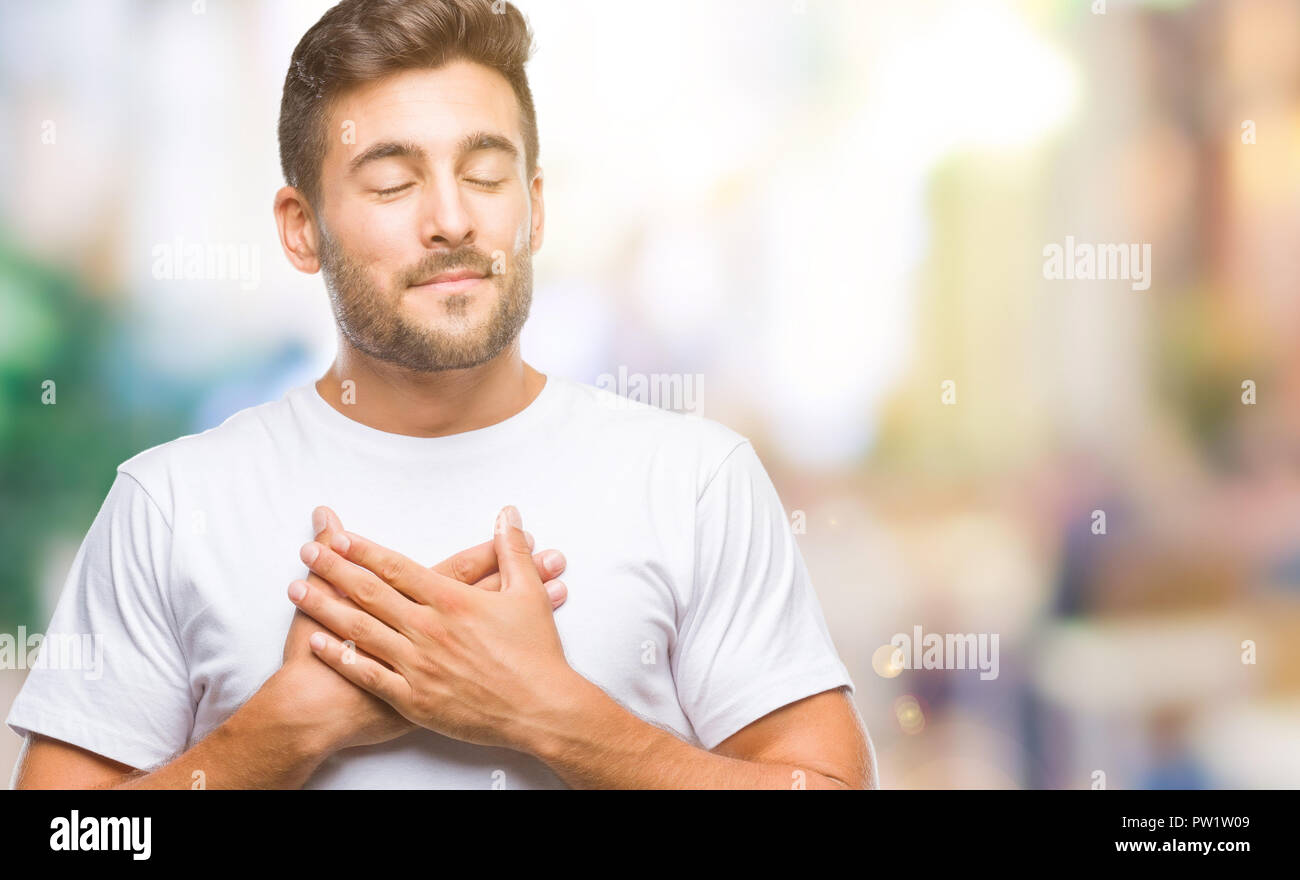 Young handsome man over isolated background smiling with hands on chest ...