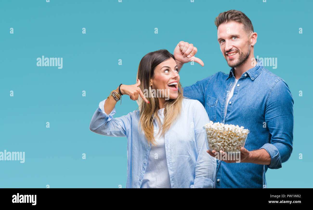 Young couple in love eating popcorn over isolated background with ...