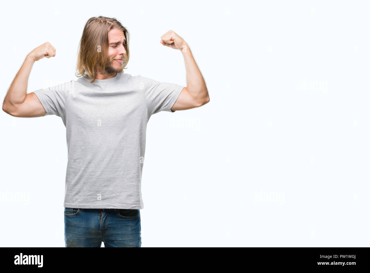 Young handsome man with long hair over isolated background showing arms ...