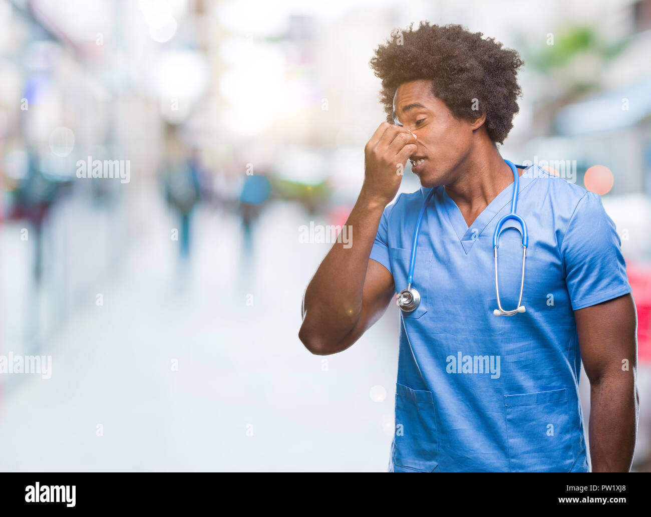 Afro american surgeon doctor man over isolated background smelling ...