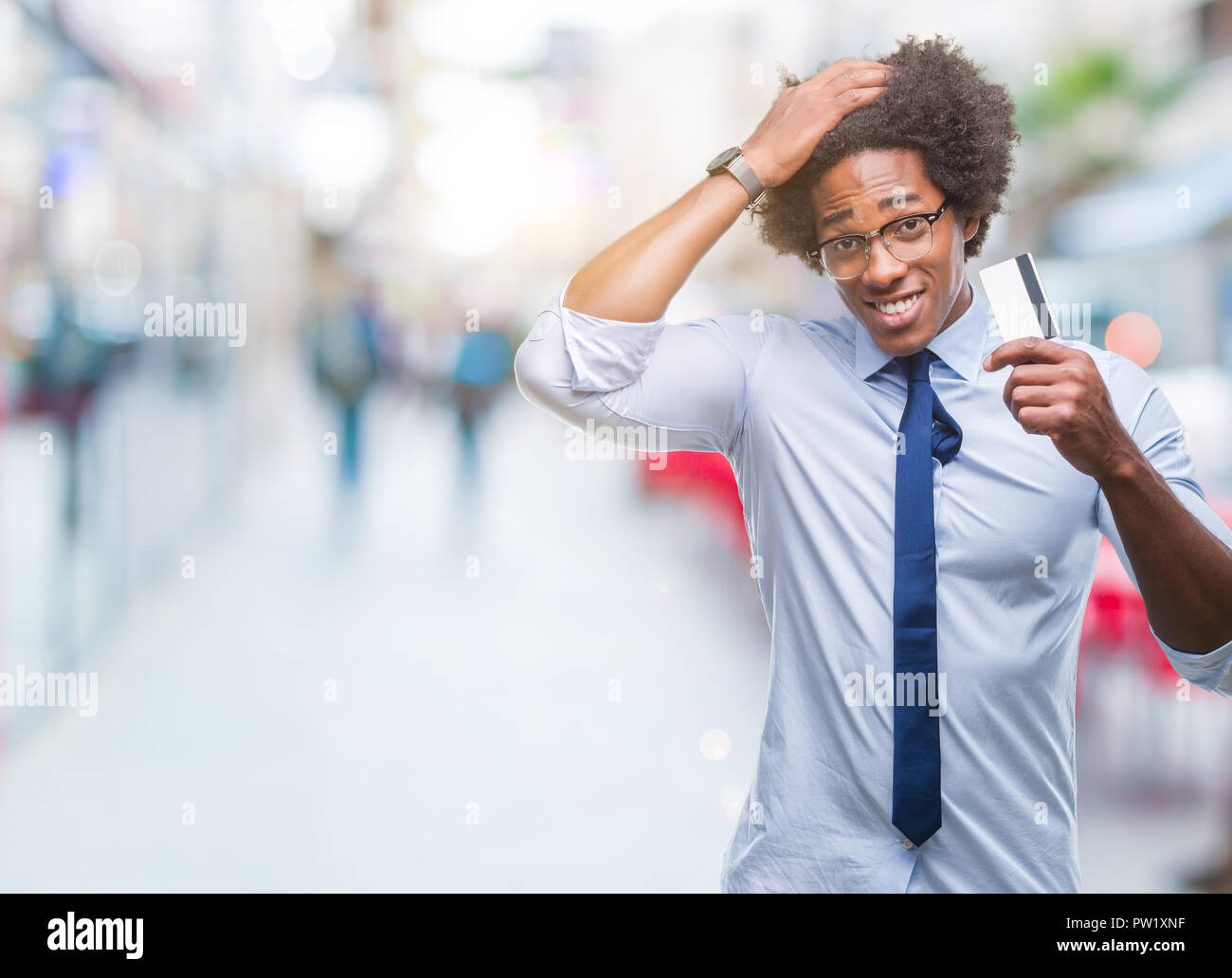 Afro american man holding credit card over isolated background stressed ...