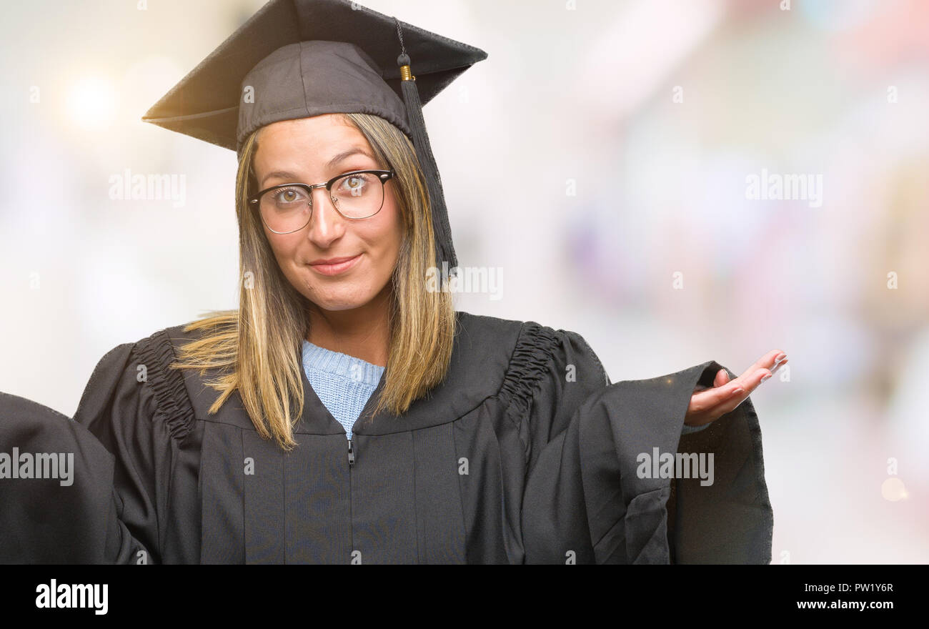Young beautiful woman wearing graduated uniform over isolated ...