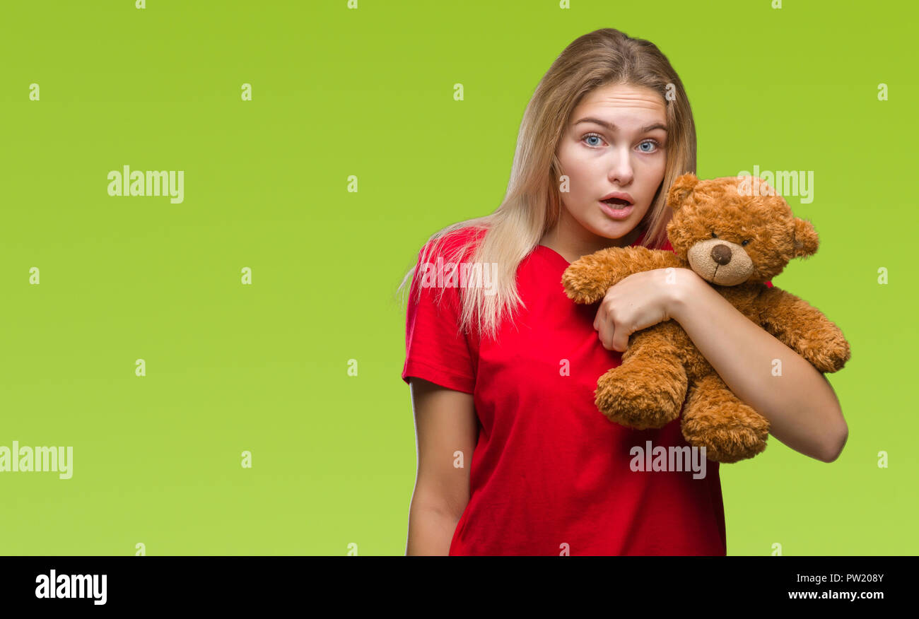 Young caucasian woman holding cute teddy bear over isolated background ...