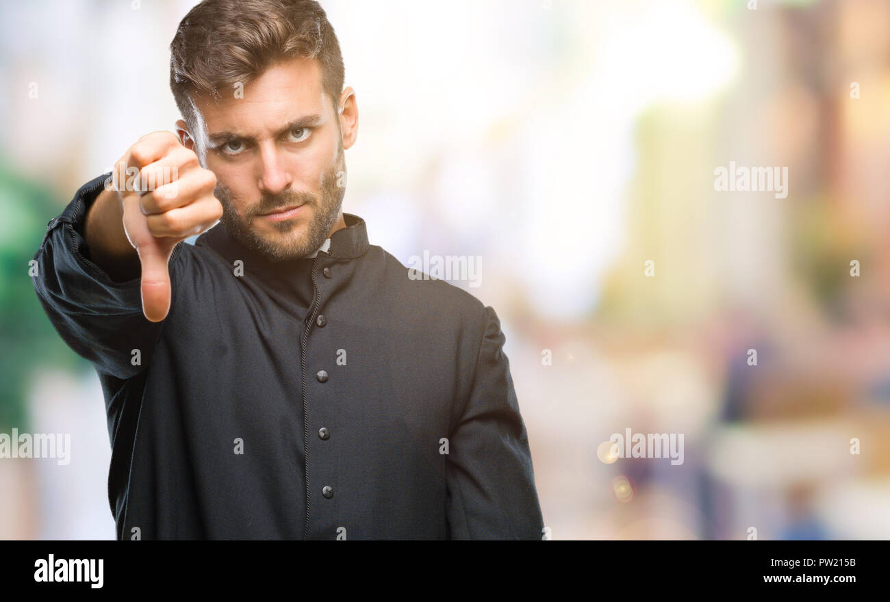 Young catholic christian priest man over isolated background looking ...