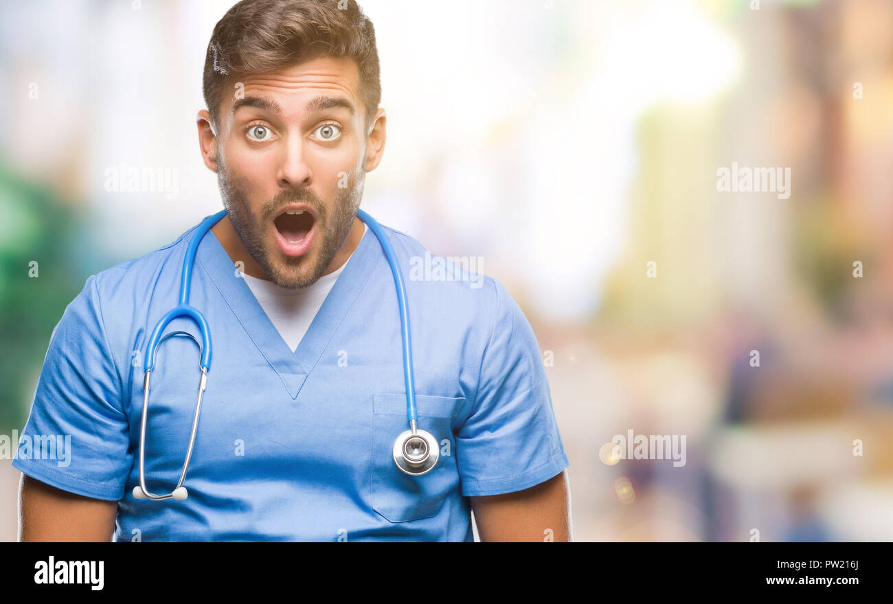 Young handsome doctor nurse man over isolated background afraid and ...