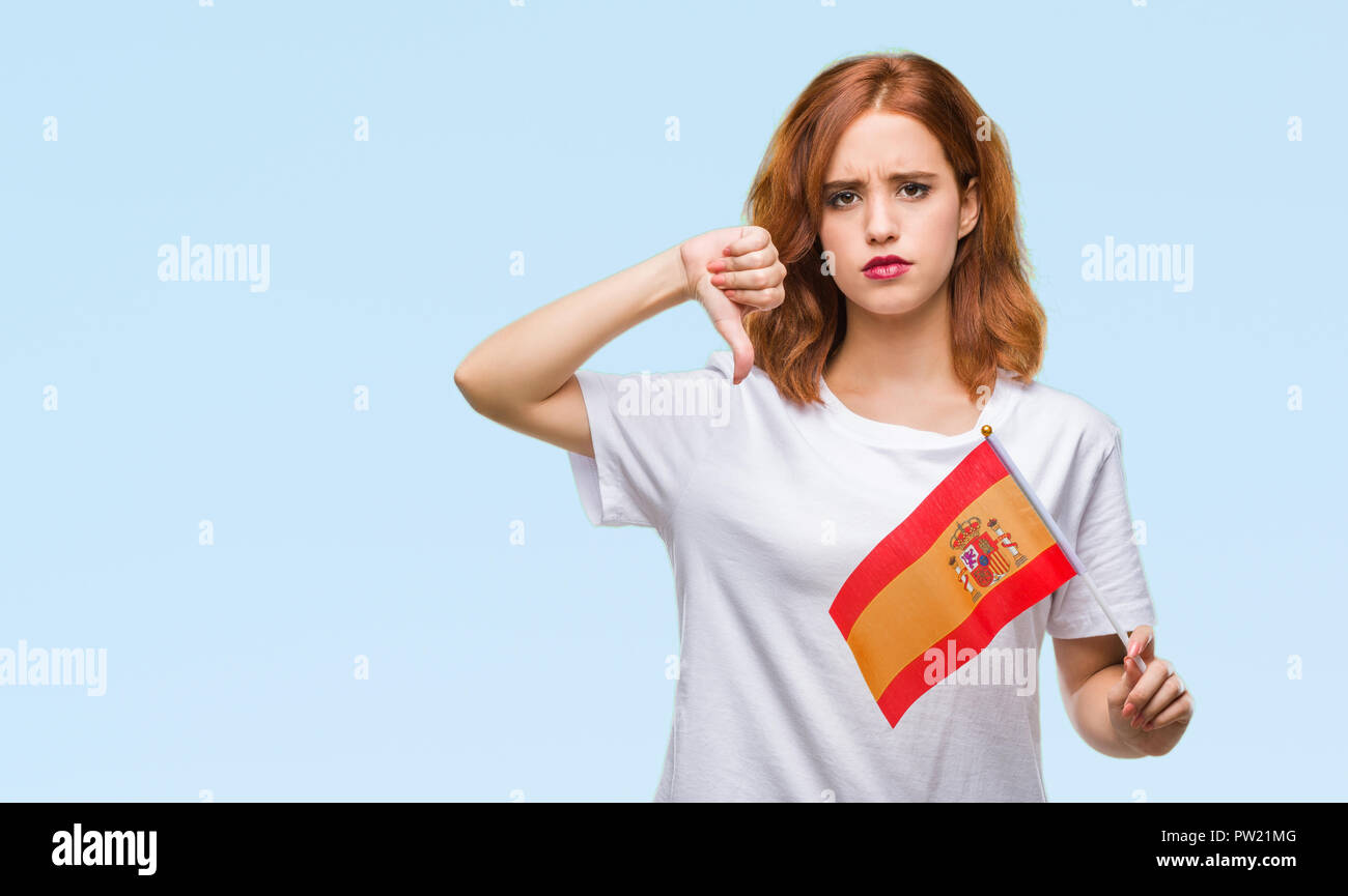 Young beautiful woman holding flag of spain over isolated background ...