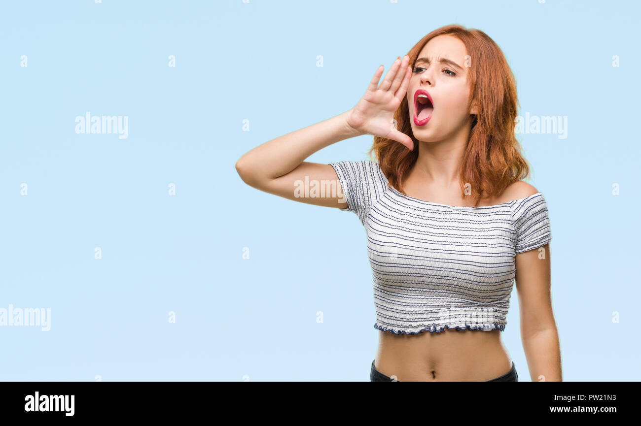 Young beautiful woman over isolated background shouting and screaming ...