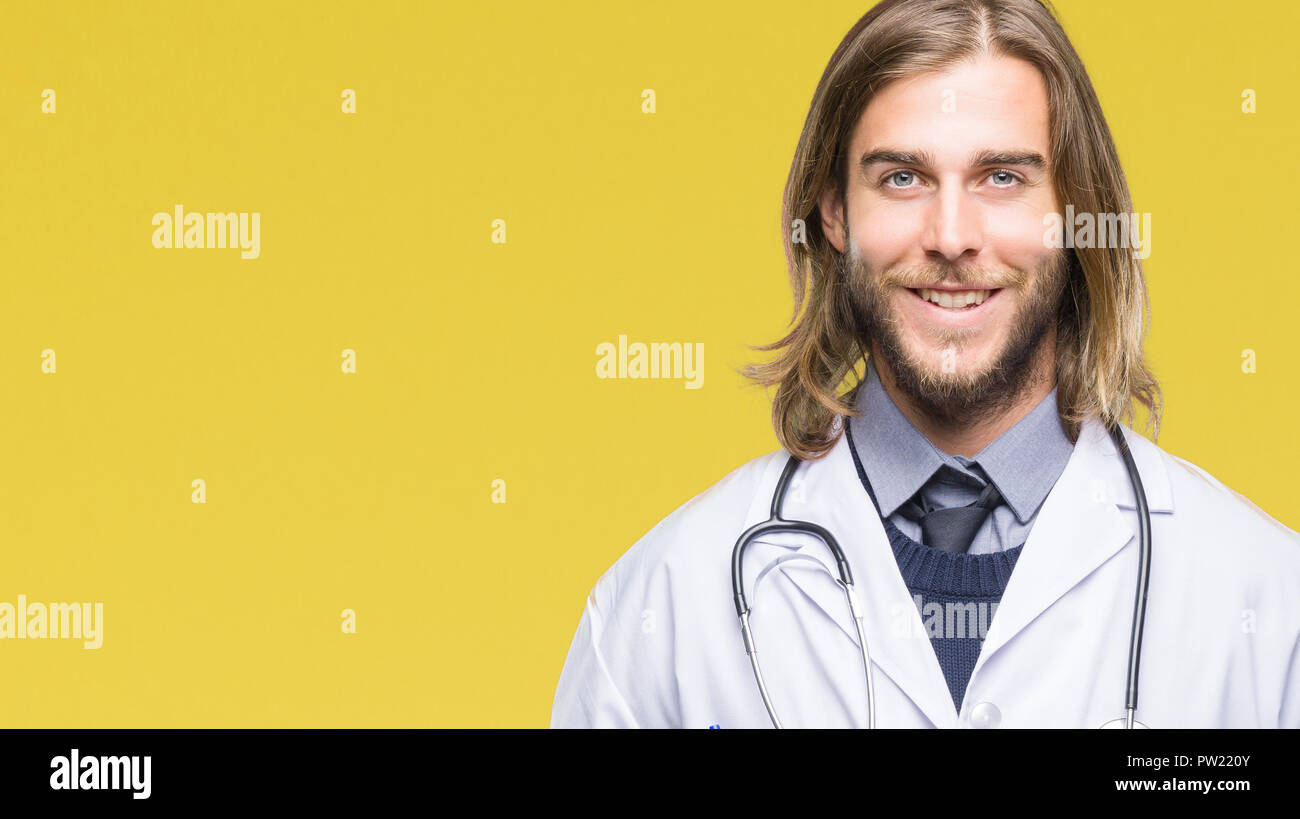 Young handsome doctor man with long hair over isolated background with ...