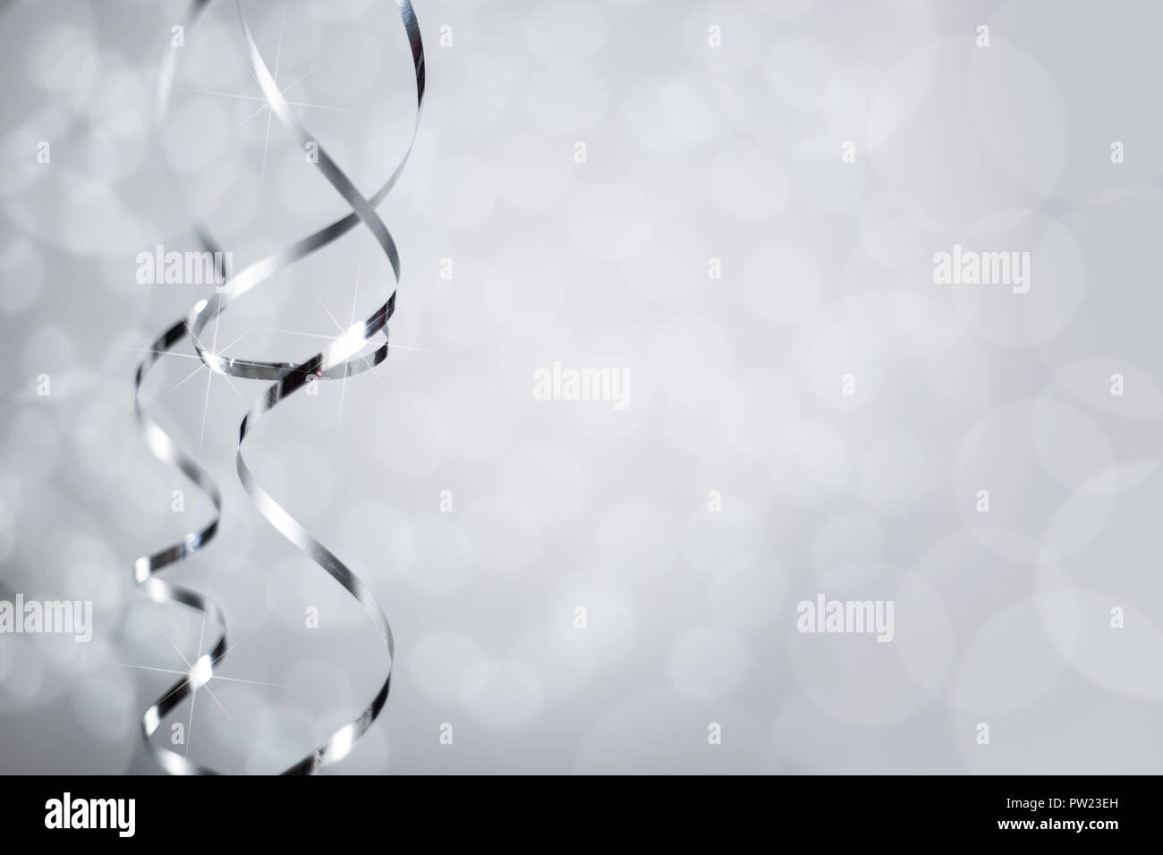 Silver Christmas new year curly streamer ribbon over glittering bokeh ...