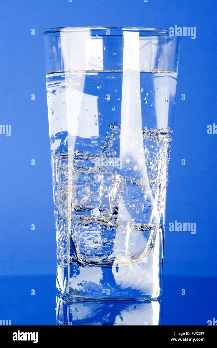 glass with cold water and ice on blue background Stock Photo - Alamy