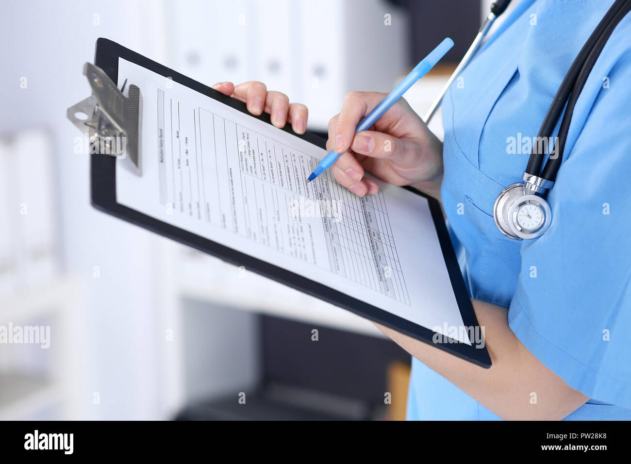 Female doctor filling up medical form on a clipboard, closeup ...