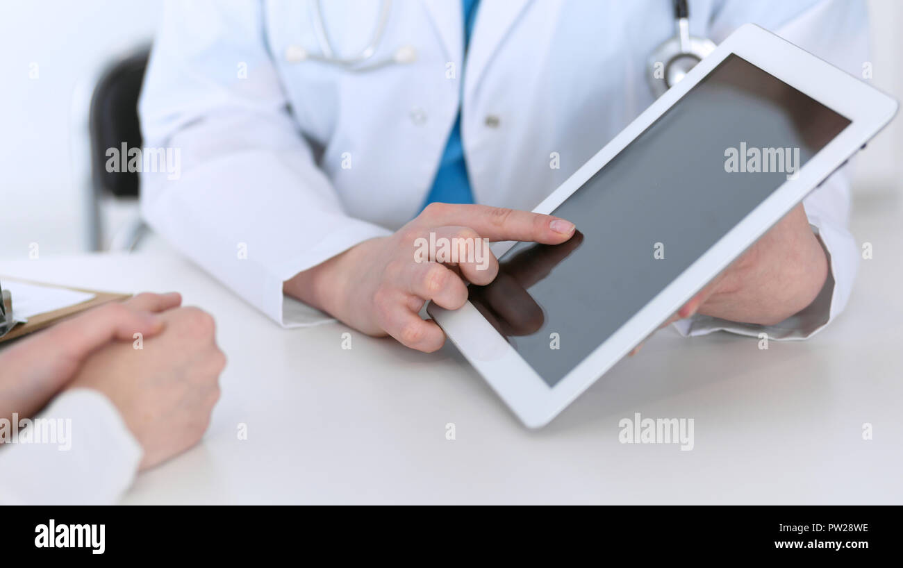 Closeup of a doctor and patient sitting at the desk. Physician pointing ...
