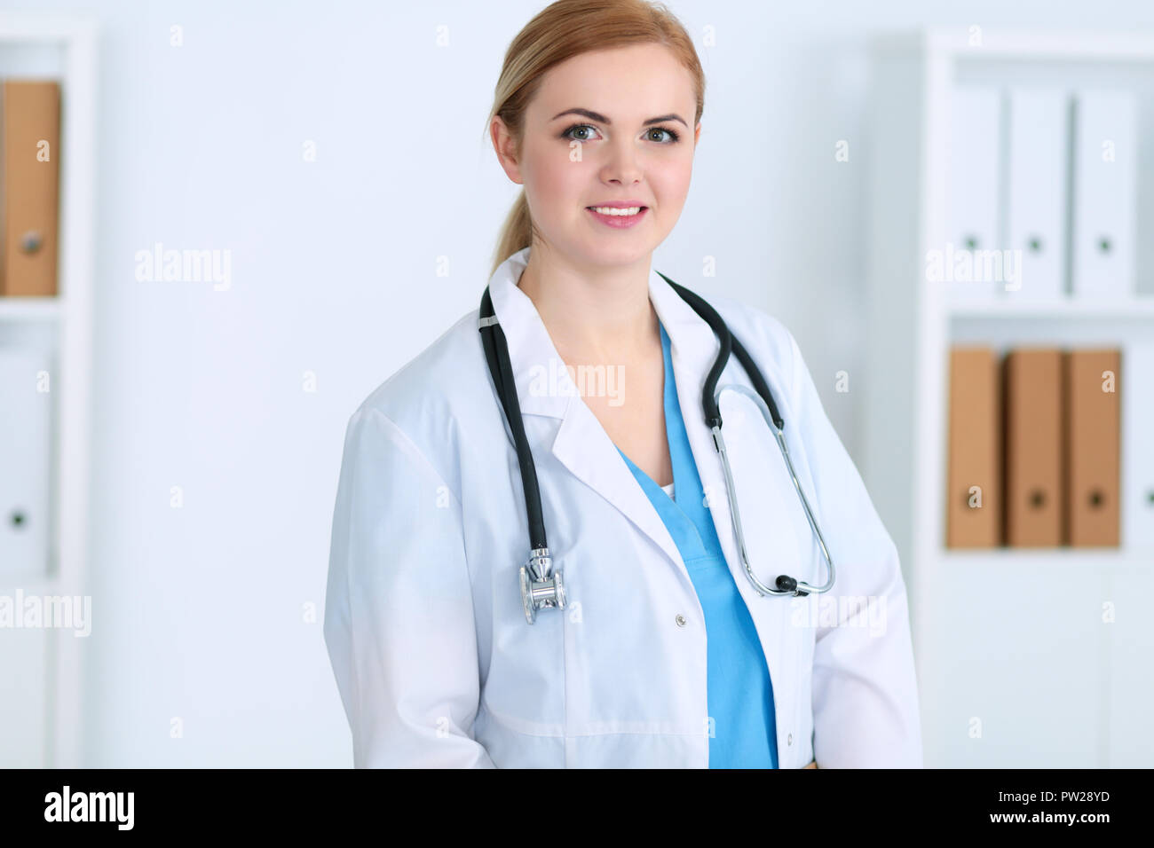 Beautiful female medical doctor standing at hospital. Physician is ...