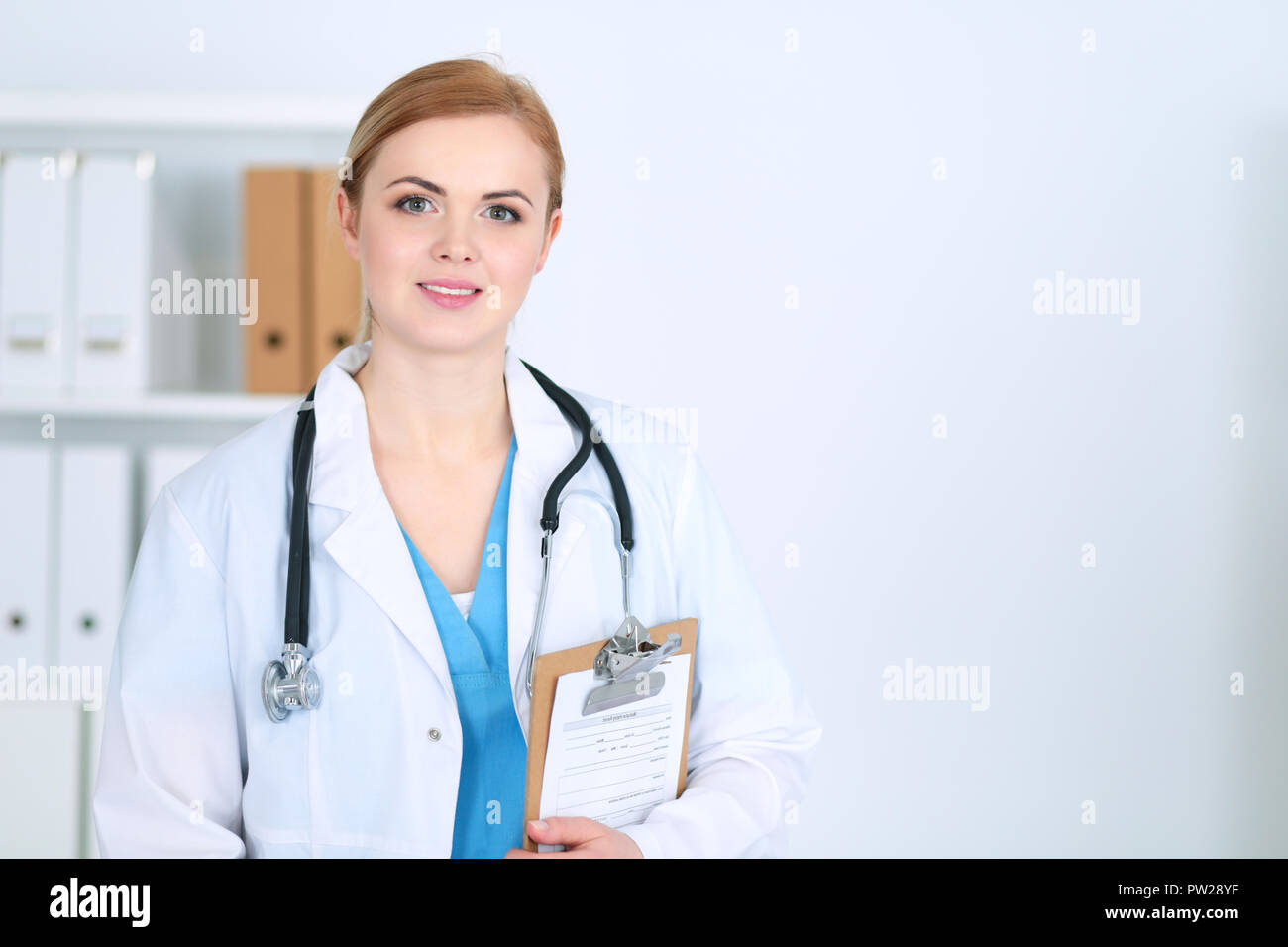 Beautiful female medical doctor standing at hospital. Physician is ...