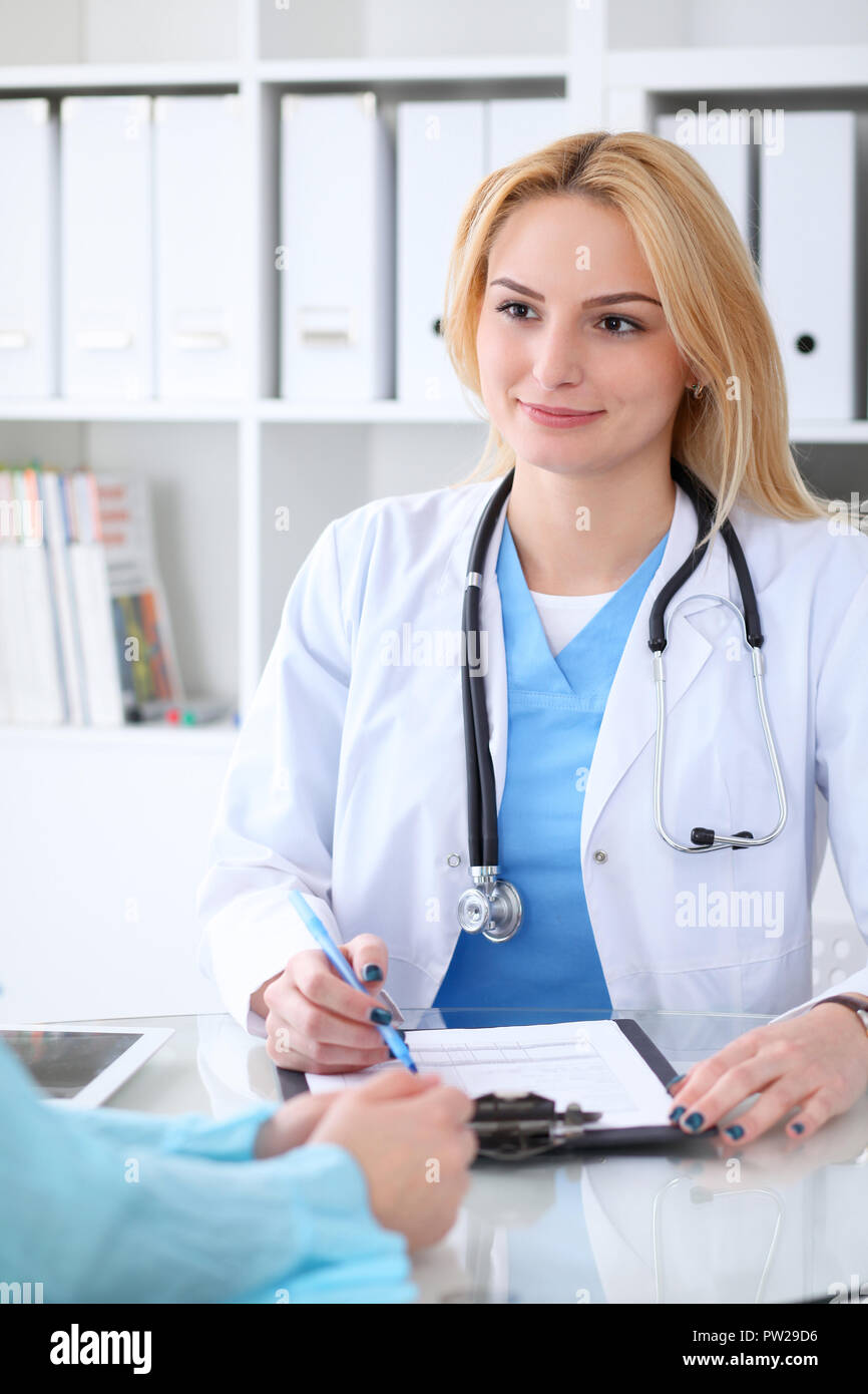 Doctor and patient discussing something while sitting at the table at ...