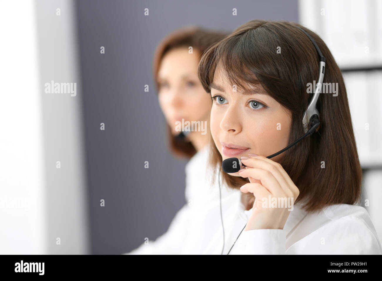 Call center. Group of operators at work. Focus on young brunette woman ...