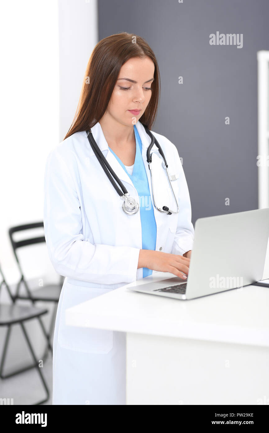 Doctor woman at work. Portrait of female physician using laptop ...